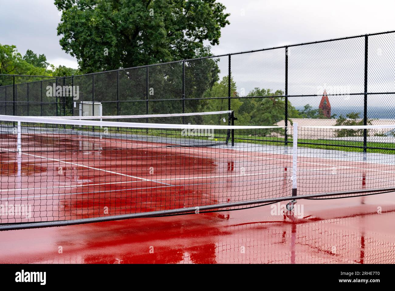 New portable pickleball nets on a wet red tennis court with white lines ...