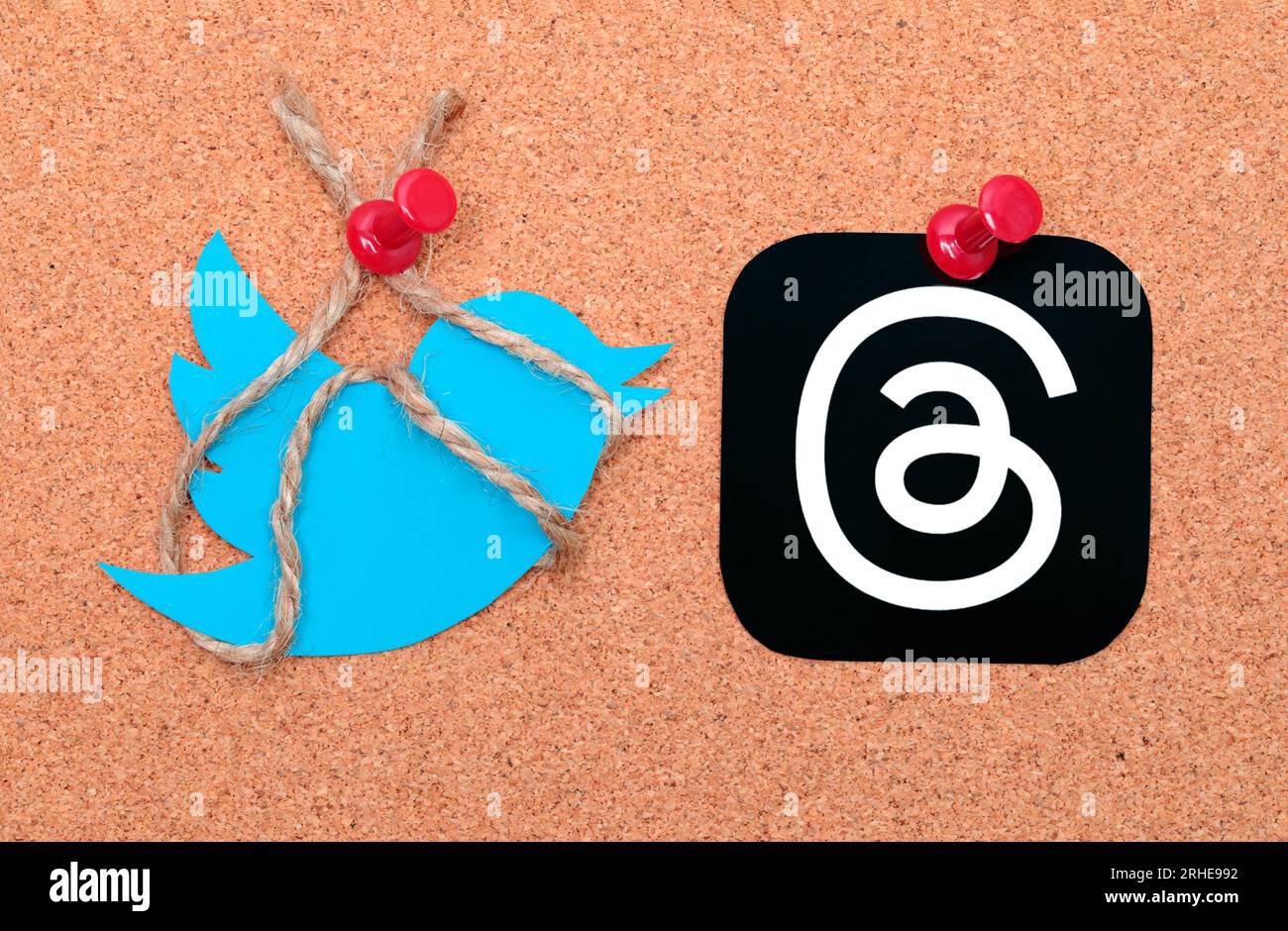 Threads mobile app icon and tied Twitter logo pinned on cork tree ...