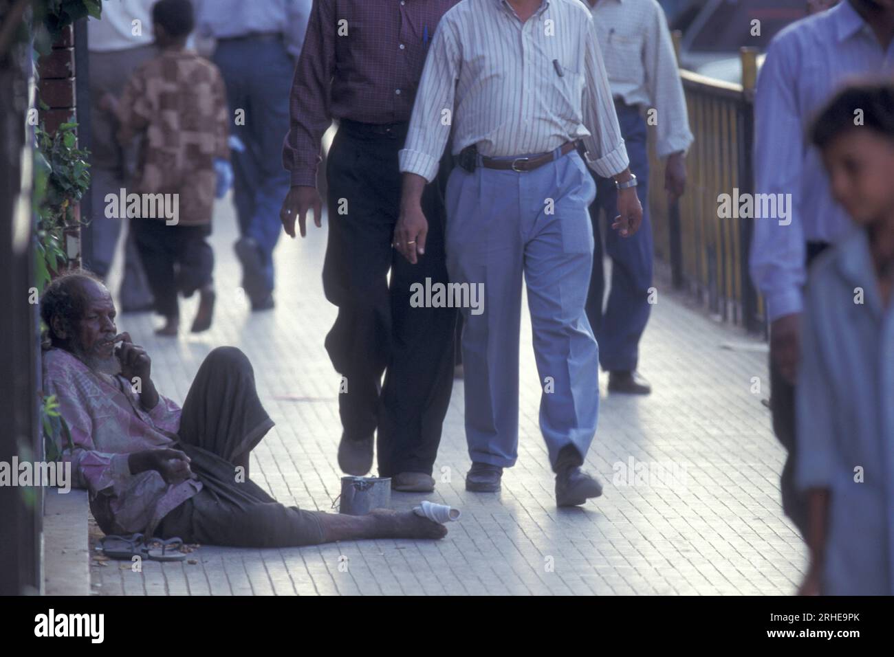 a poor Indian men on a Road with Shops and Traffic in the city of ...