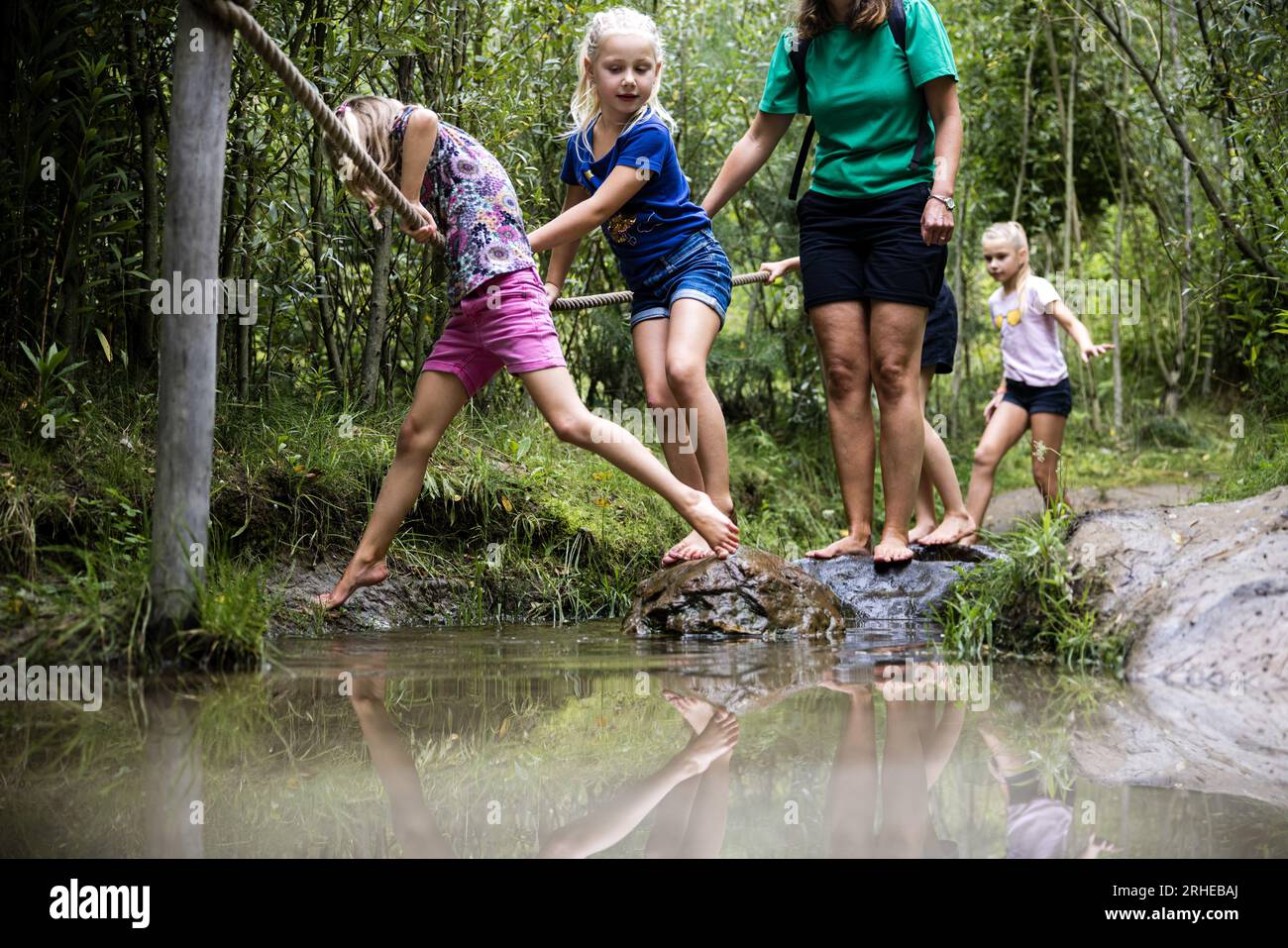 BRUNSSUM - Visitors to the barefoot park walk through a mud puddle ...