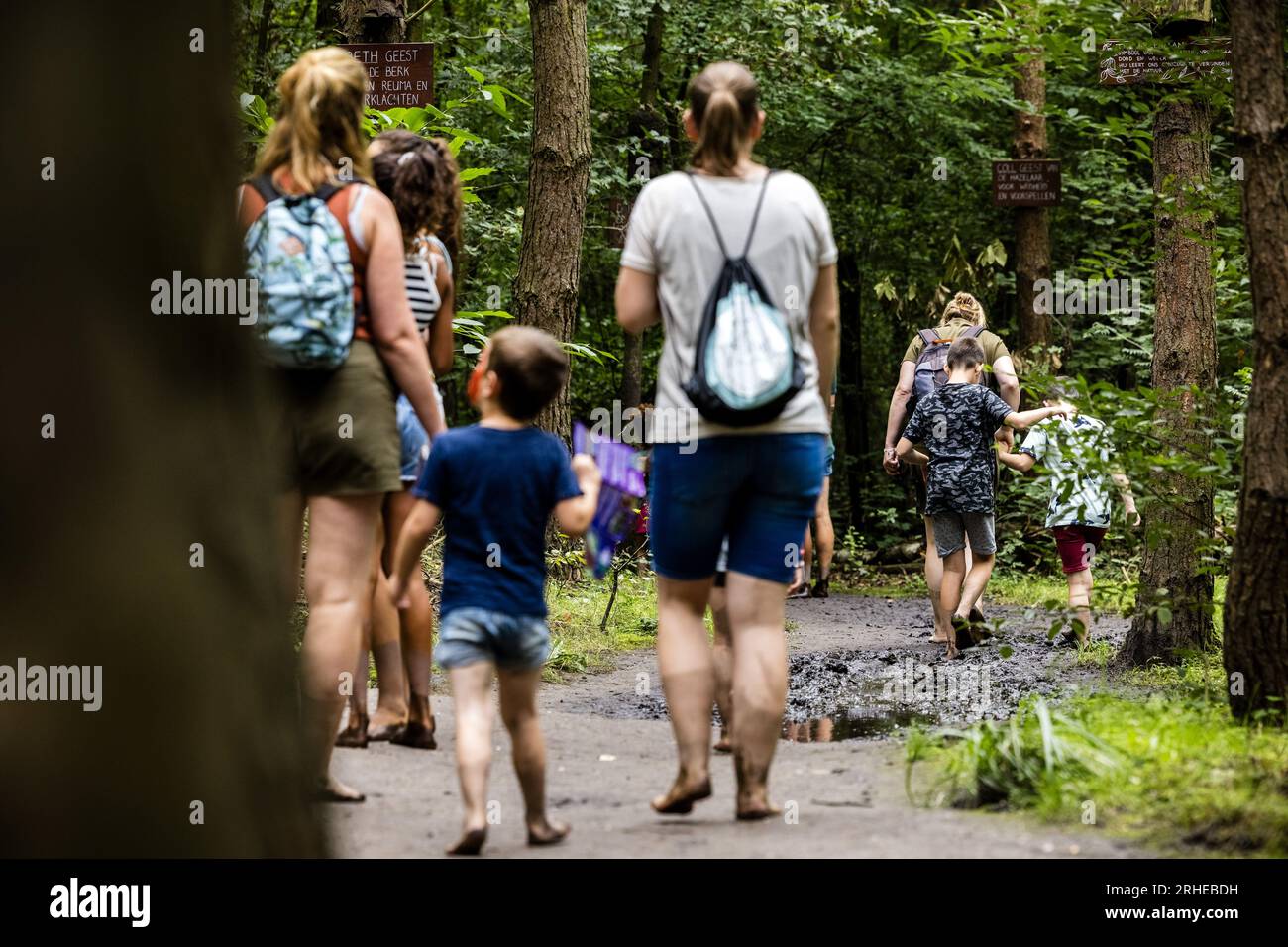 BRUNSSUM - Visitors to the barefoot park walk through a mud puddle ...