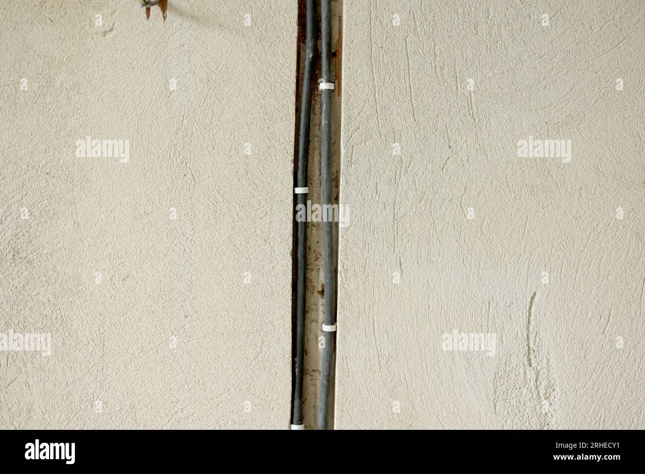 Wiring electrical cables on building concrete wall. Unfinished room ...
