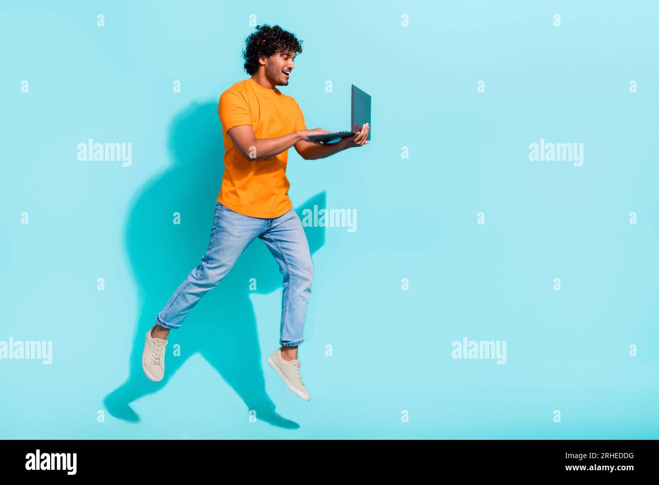 Full body profile photo of excited person jumping hold use netbook ...
