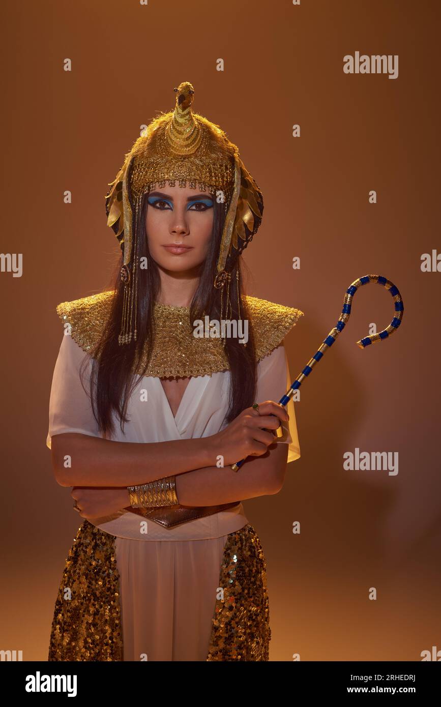 Brunette woman in egyptian attire and headdress holding crook and ...