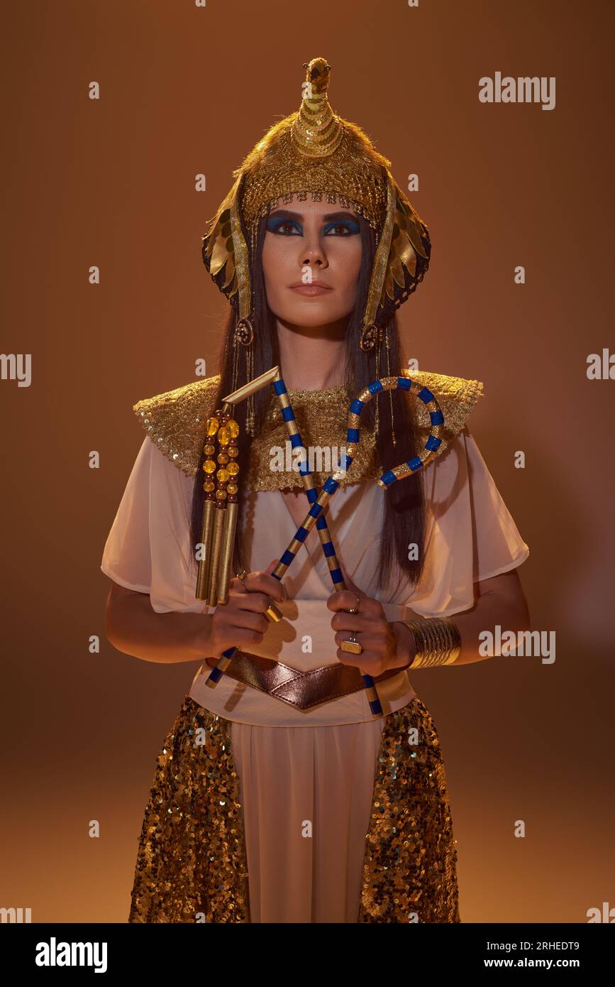 Stylish woman in egyptian headdress and look holding crook and flail on ...