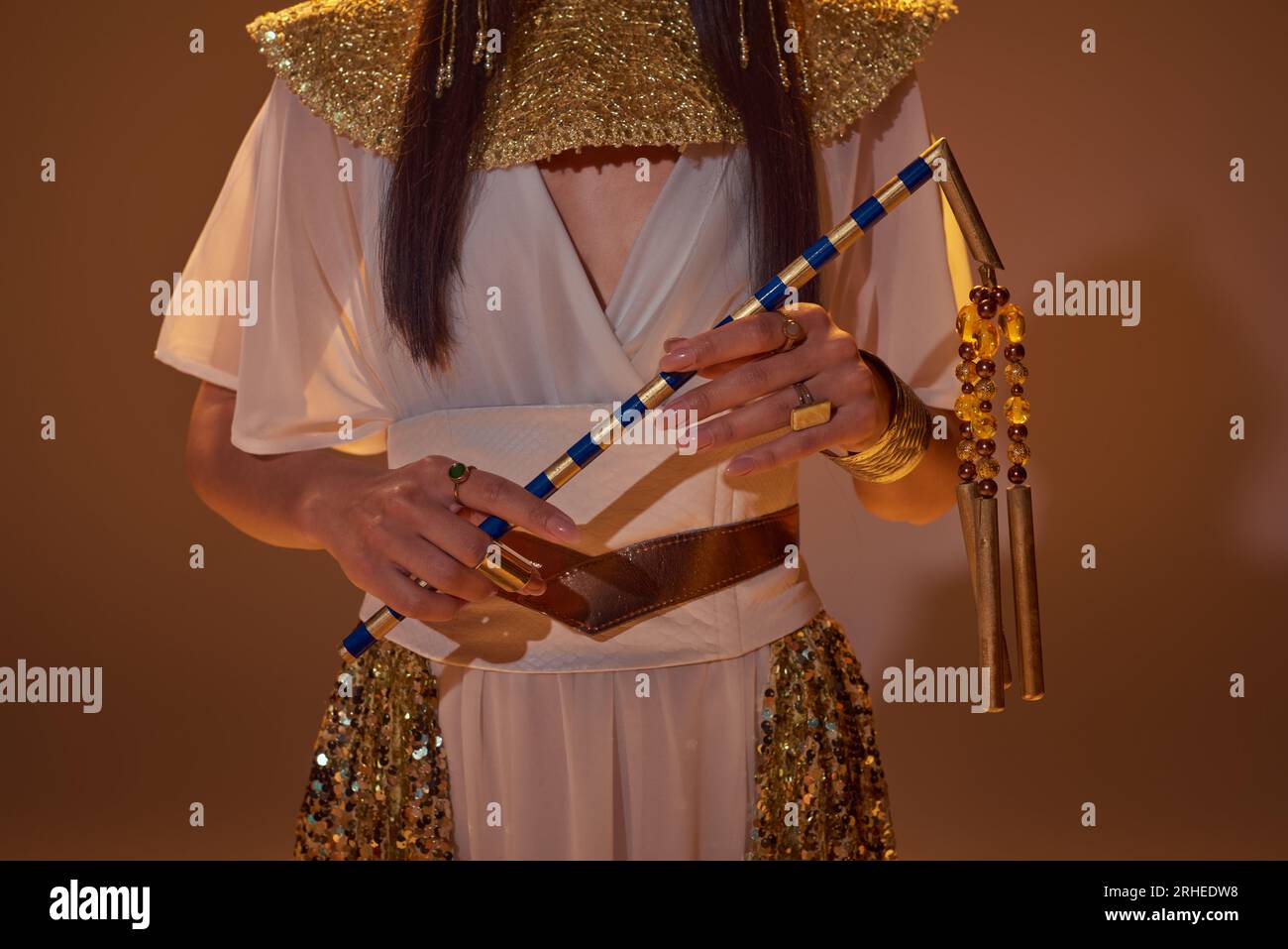 Cropped view of woman in egyptian outfit holding flail while posing on ...