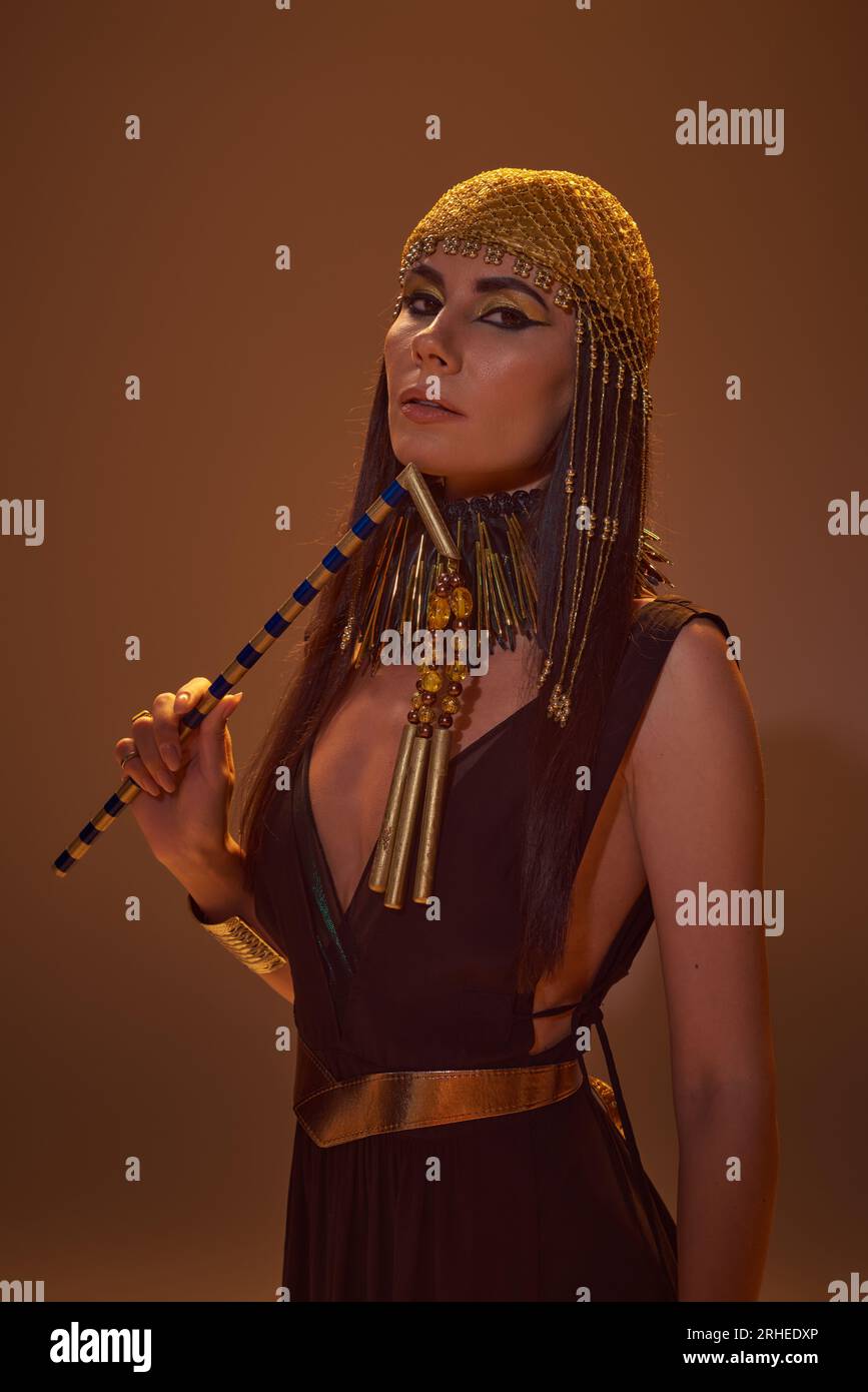 Elegant woman with makeup and egyptian look holding flail and looking ...