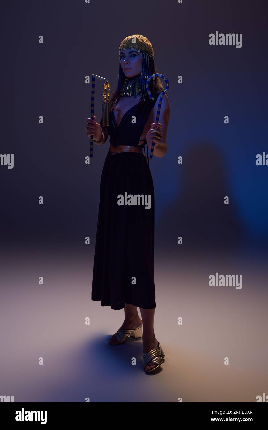 Full length of woman in egyptian look holding flail and crook and ...