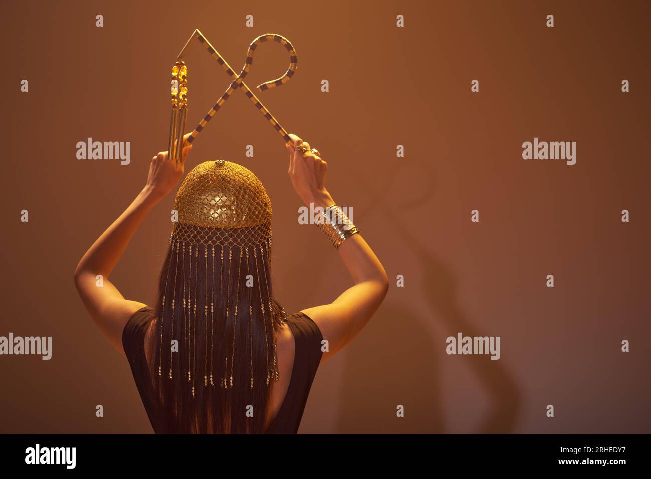 Back view of brunette woman in egyptian headdress holding crook and ...