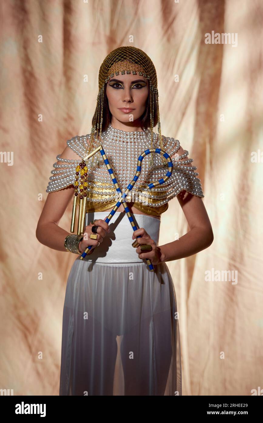 Woman in egyptian costume and pearl top holding crook and flail while ...