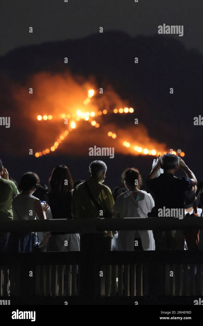 People admire the spectacle of the Gozan Okuribi bonfires in Kita Ward ...