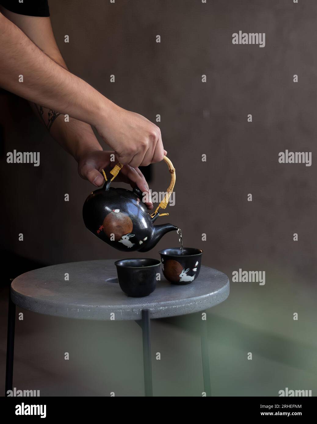 serving tea with a special ceramic teapot over two small tea cups, on a ...