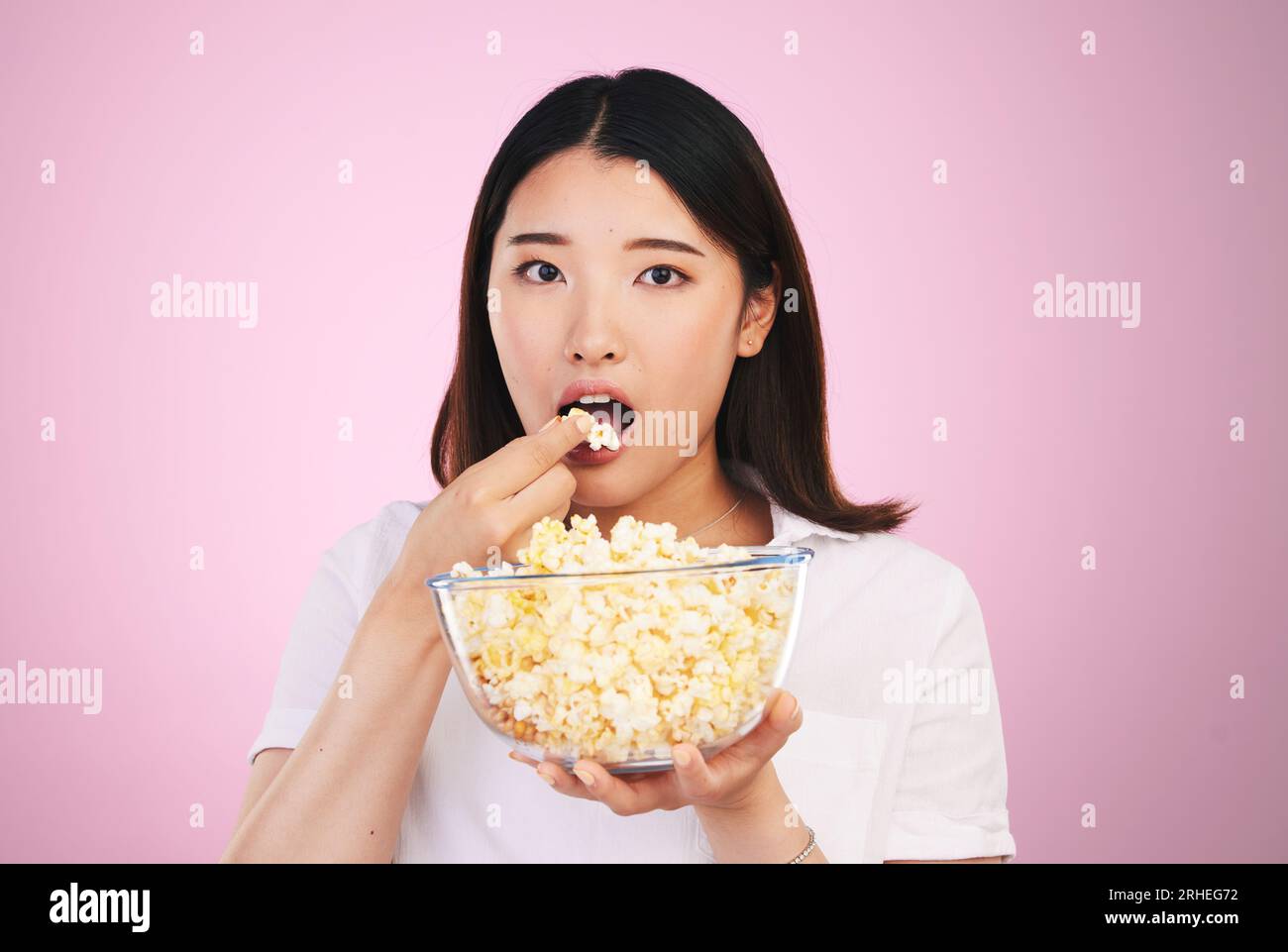 Popcorn, hungry and woman portrait eating a movie snack in a studio with watching tv and food ...