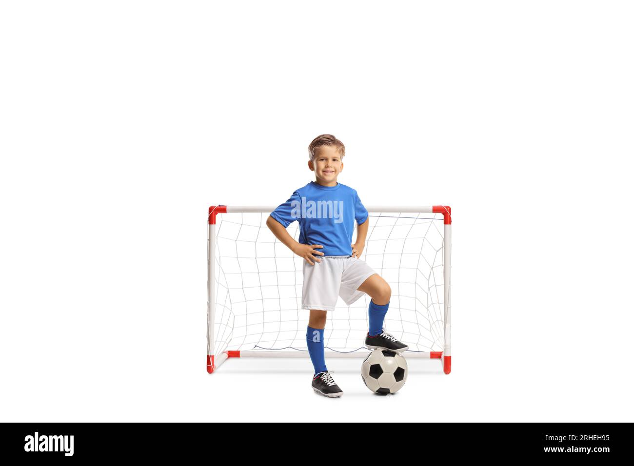 Boy in a sports jersey stepping on a soccer ball in front of a mini ...