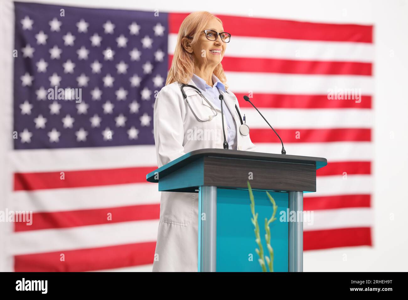 Female doctor giving a speech on a pedestal in front of the USA flag ...