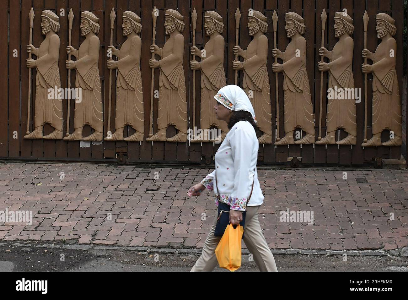 Mumbai, India. 16th Aug, 2023. A Parsi woman walks past the carvings of ...