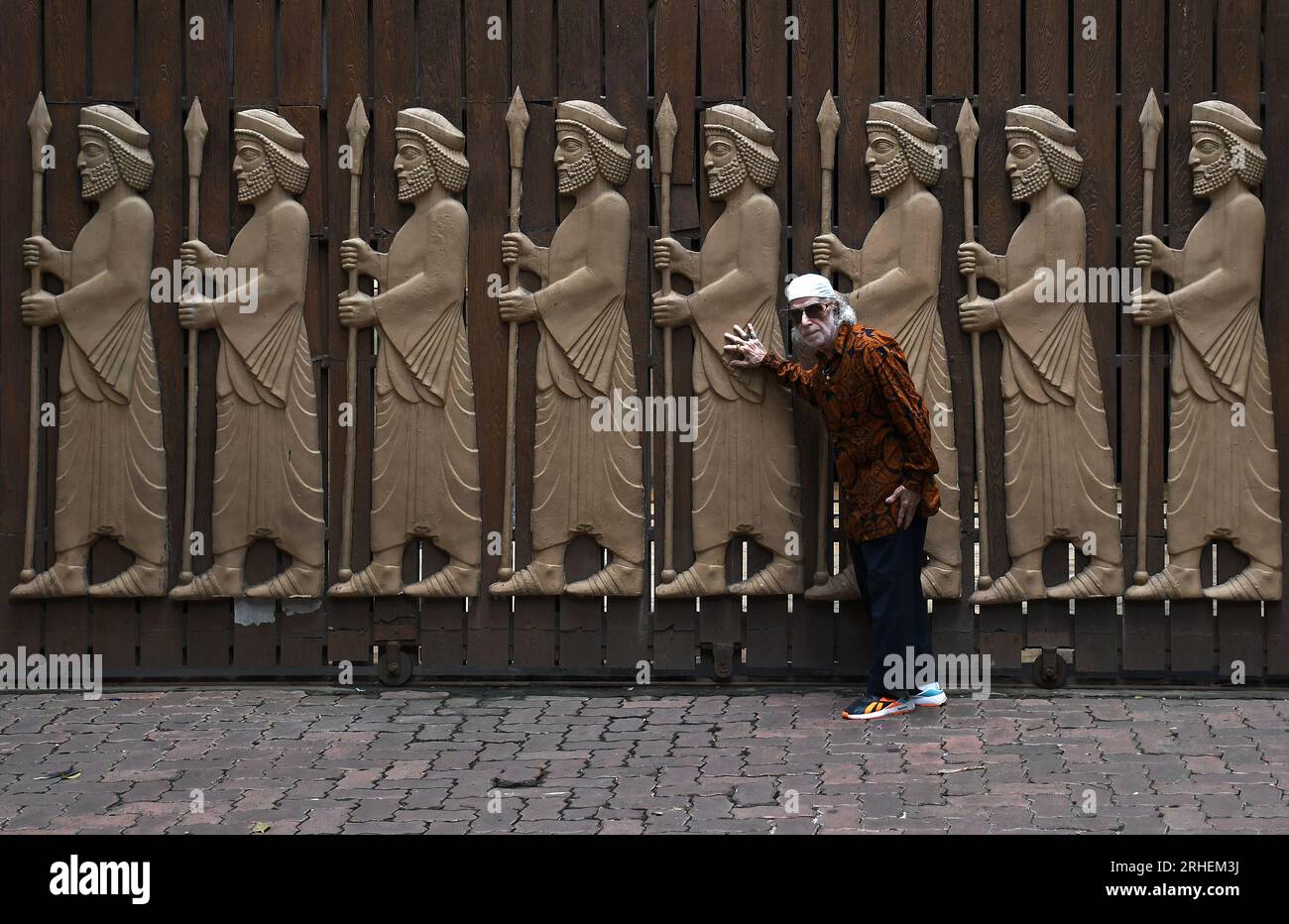 A Parsi man poses for a photo near the carvings of guardians of faith ...
