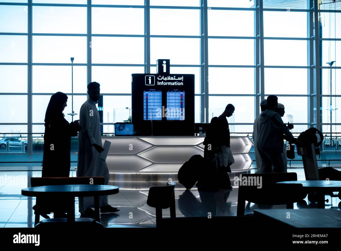 Bahrain airport interior. Passengers passing in silhouette, backlit ...