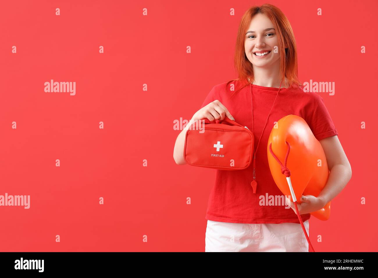 Female lifeguard with rescue buoy and first aid kit on red background ...