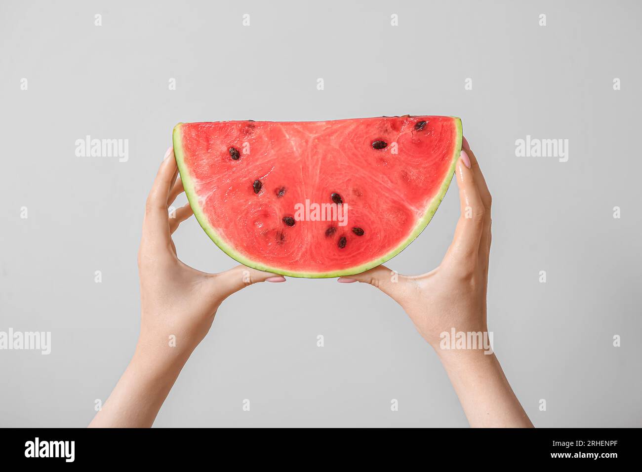 Female hands with piece of ripe watermelon on light grey background ...