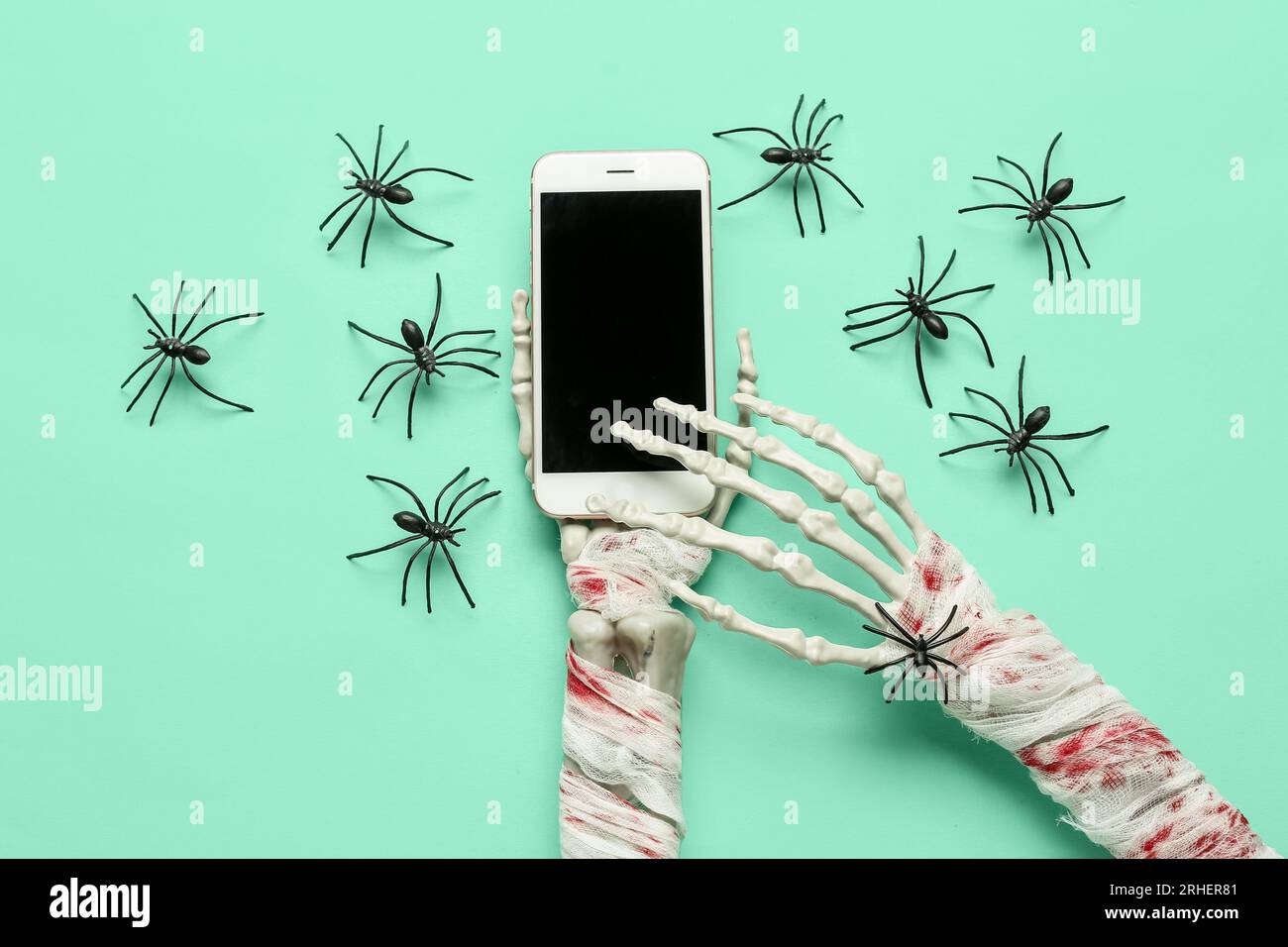 Skeleton hands with modern mobile phone and spiders for Halloween ...