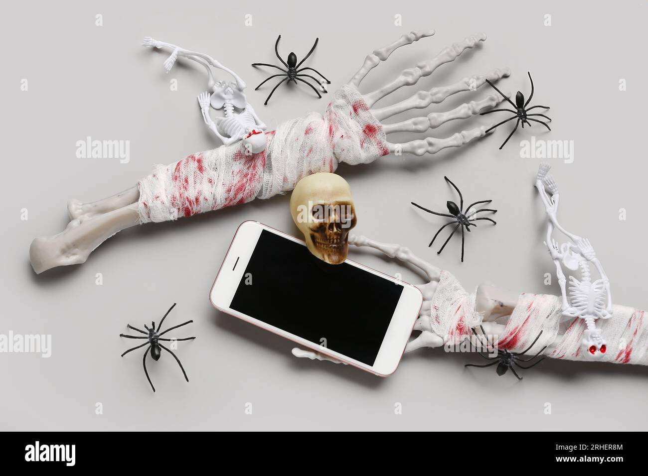 Skeleton hands with modern mobile phone, skull and spiders for ...