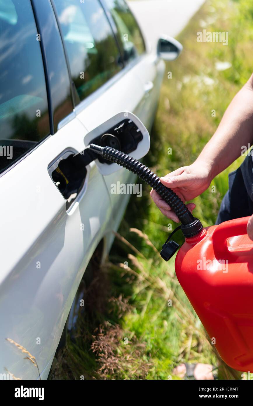The driver fills up the empty tank of the car from a red canister on ...