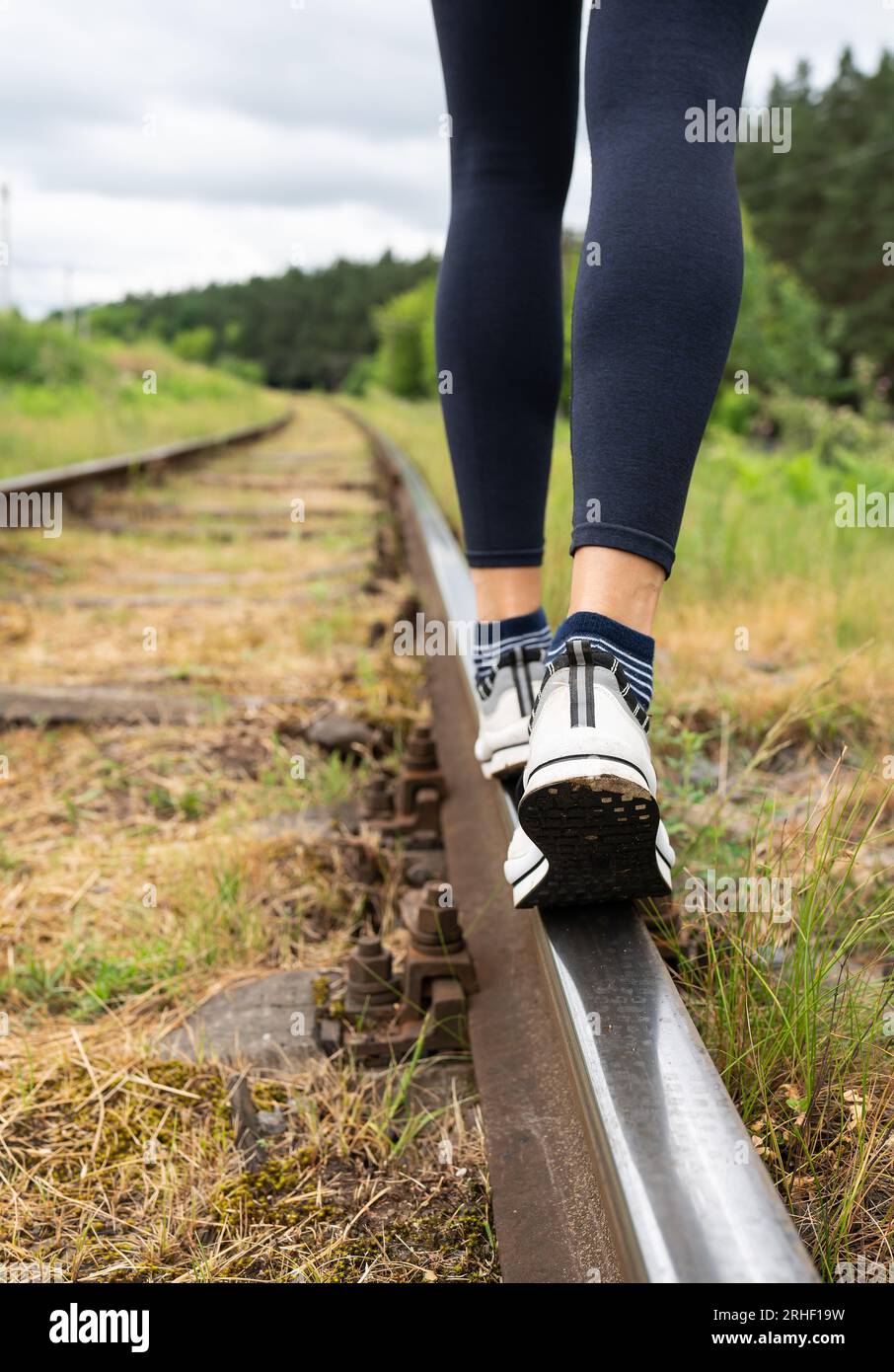 The girl is walking along the rails, rear view. Girl's legs on the ...