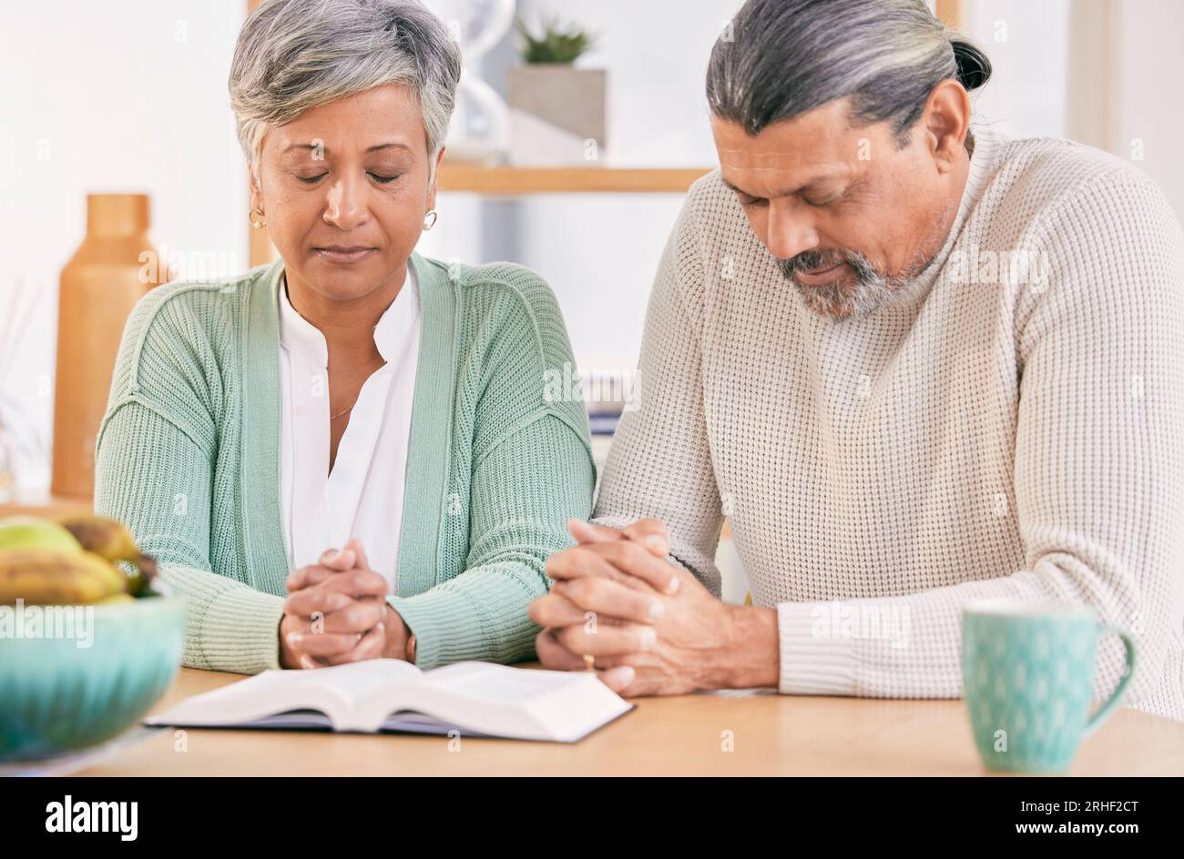 Praying, book and senior couple at home with bible study and religion ...