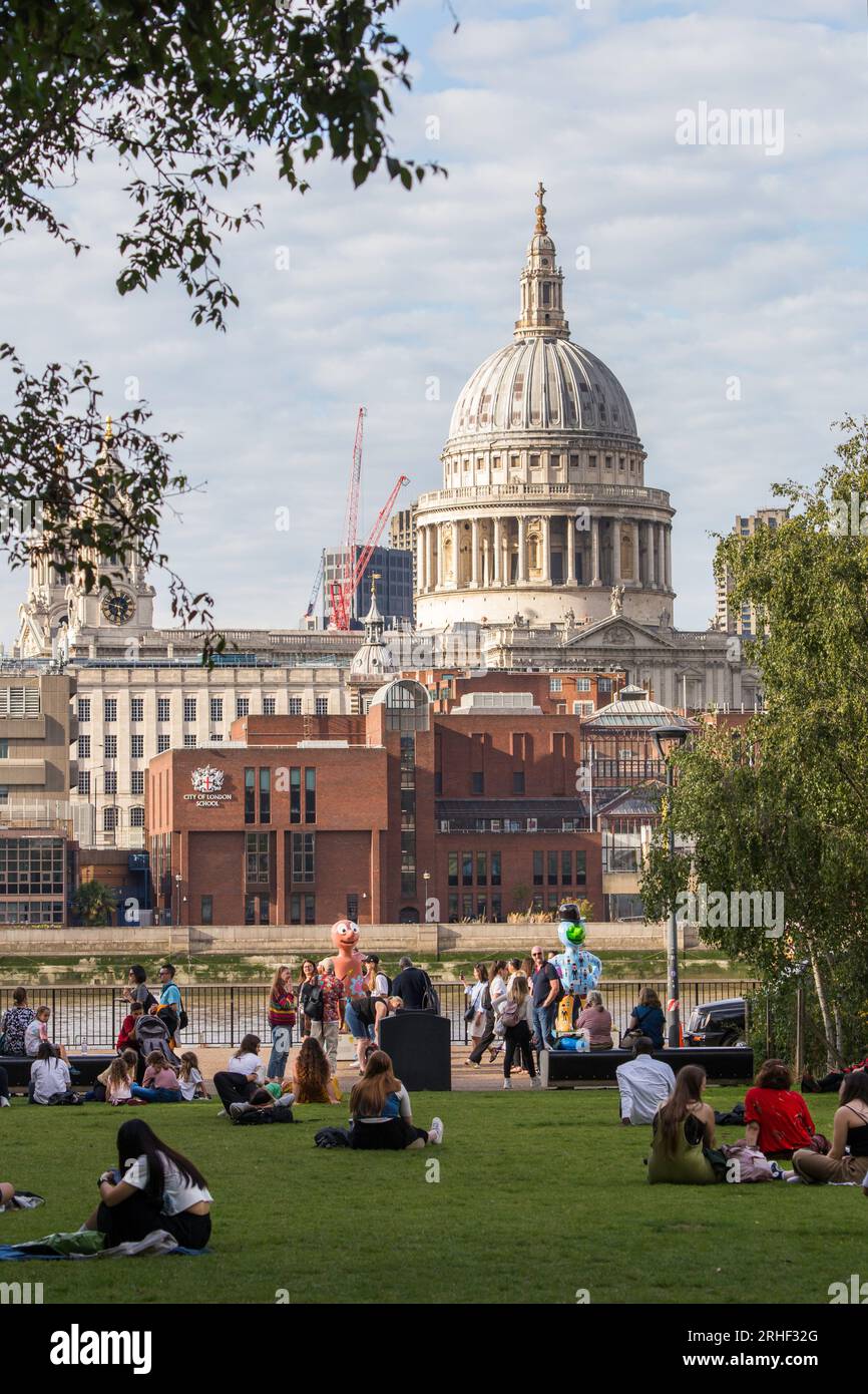 View of St Pauls from the Tate Modern with people relaxing in the sun ...