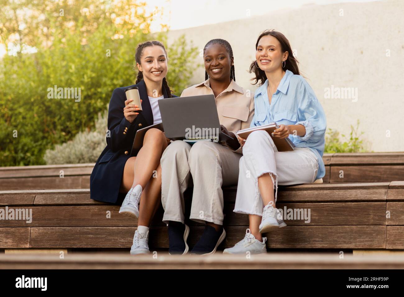 Three multicultural girlfriends students resting at university campus ...