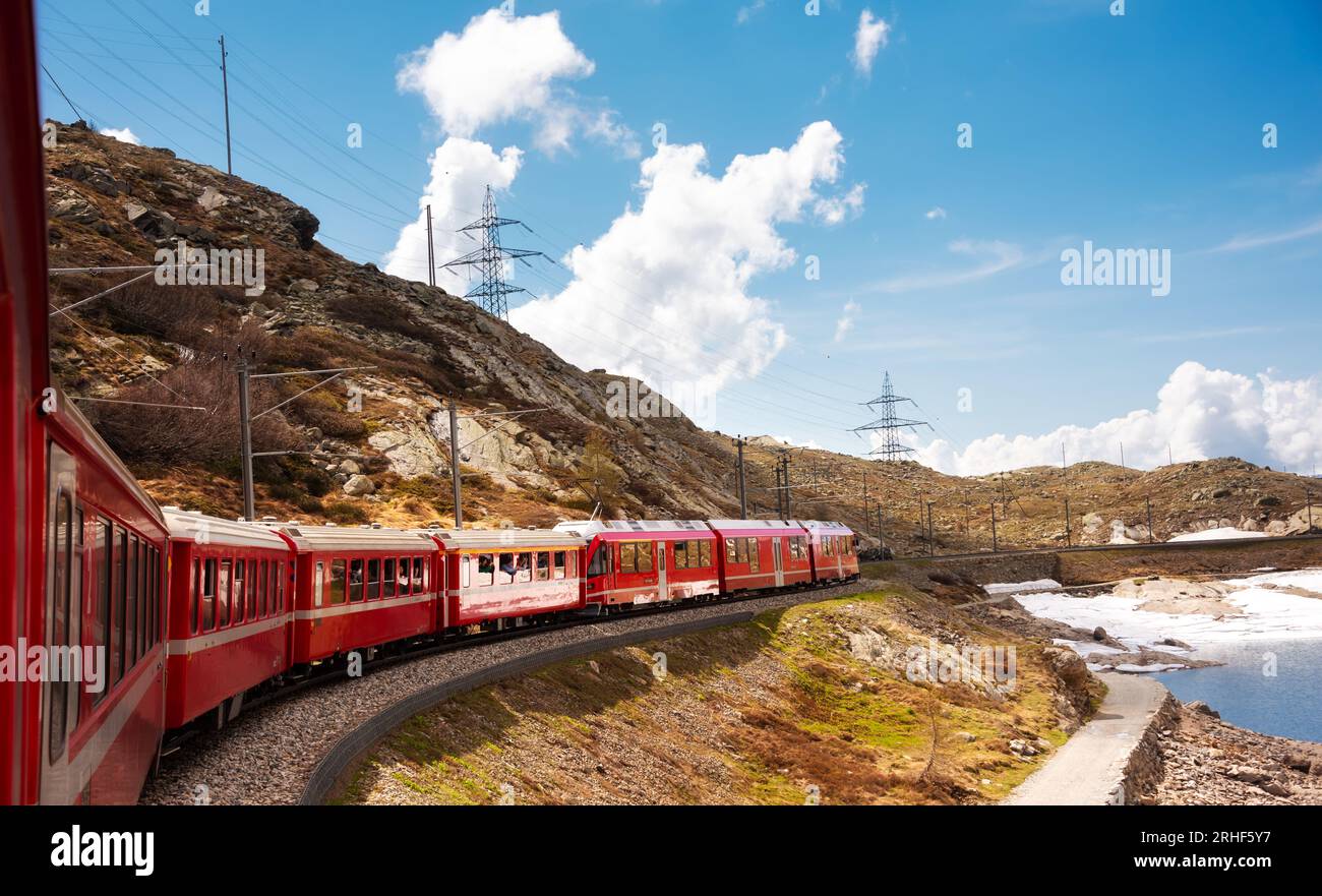 Train going along lake in Switzerland with some ice, swiss alps ...