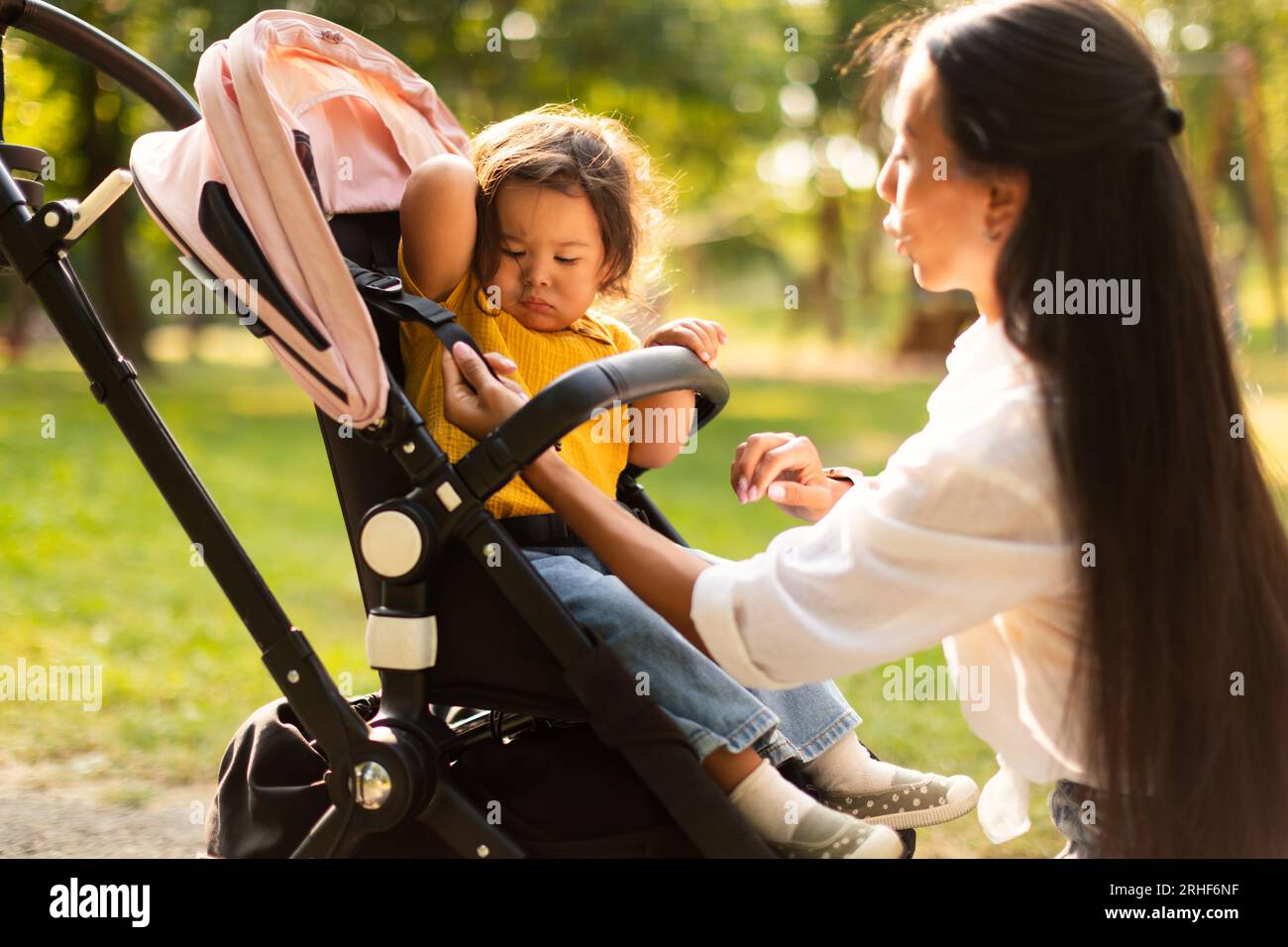 Mom Caring For Daughter's Comfort During Walk In Stroller Outside Stock ...