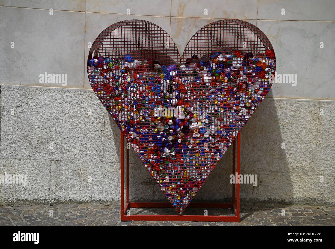 Heart shaped recycling container filled with plastic bottle caps in ...
