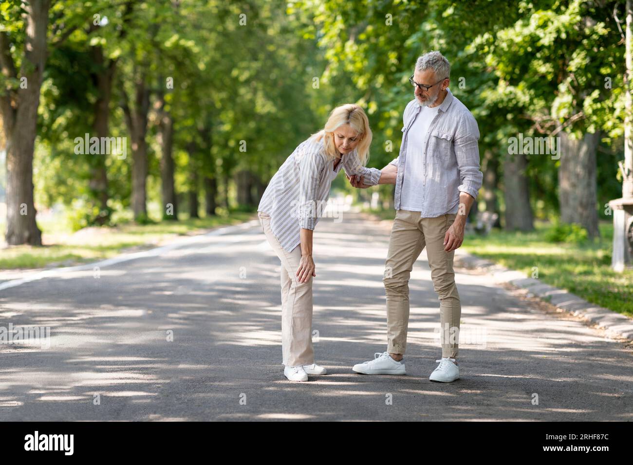 Senior Woman Suffering Knee Injury While Walking In Park With Husband ...