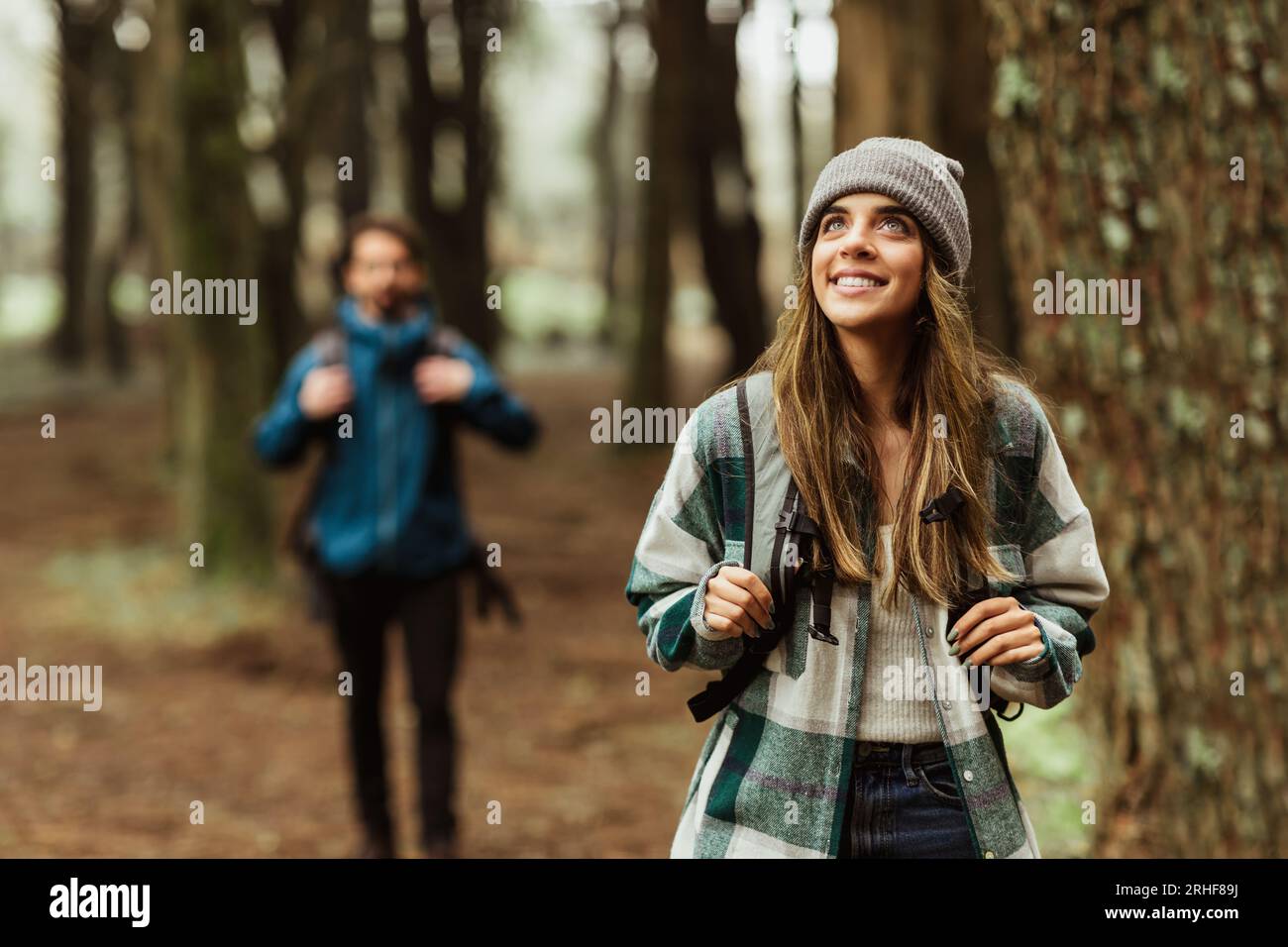 Glad inspired young caucasian couple in jackets walk in forest together ...