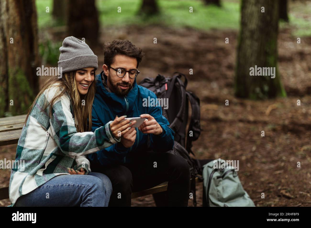 Positive young caucasian couple in jackets in forest enjoy vacation ...