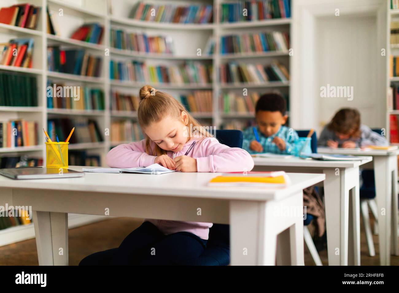 Diverse school children studying in primary school, doing homework or ...