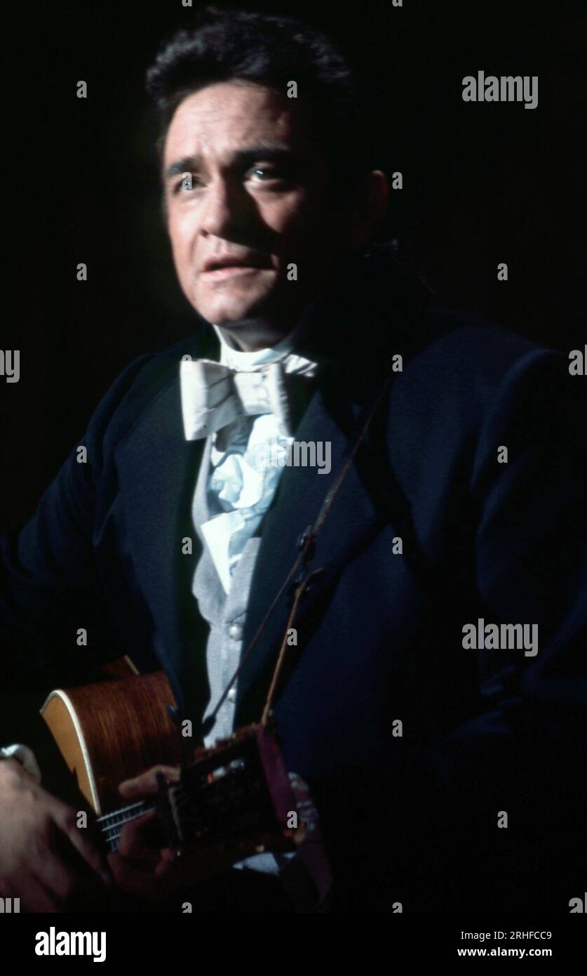 Johnny Cash in close-up playing his guitar wearing a white bowtie ...