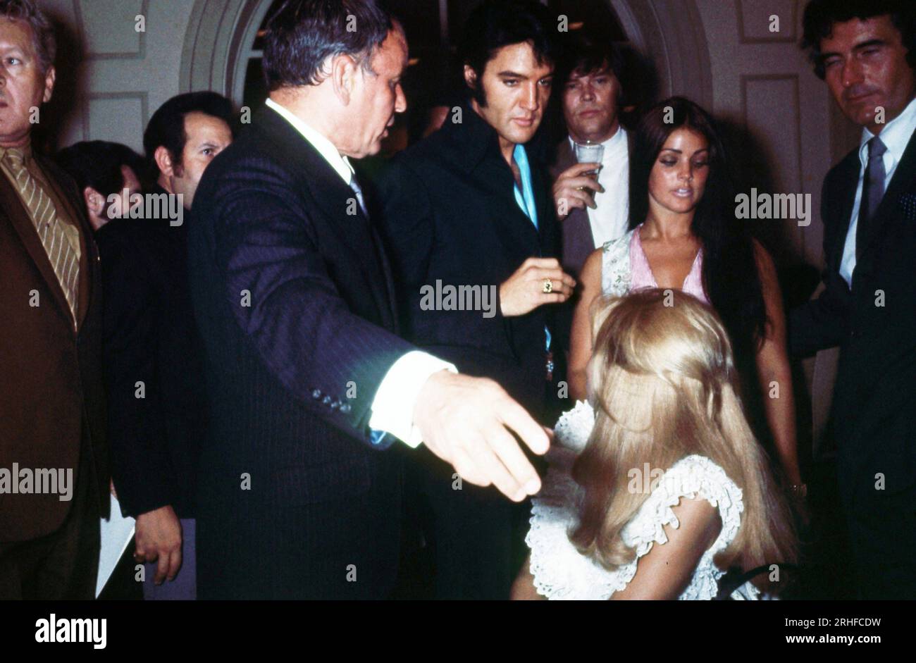 Elvis Presley wearing black jacket, walking through a crowd with wife ...