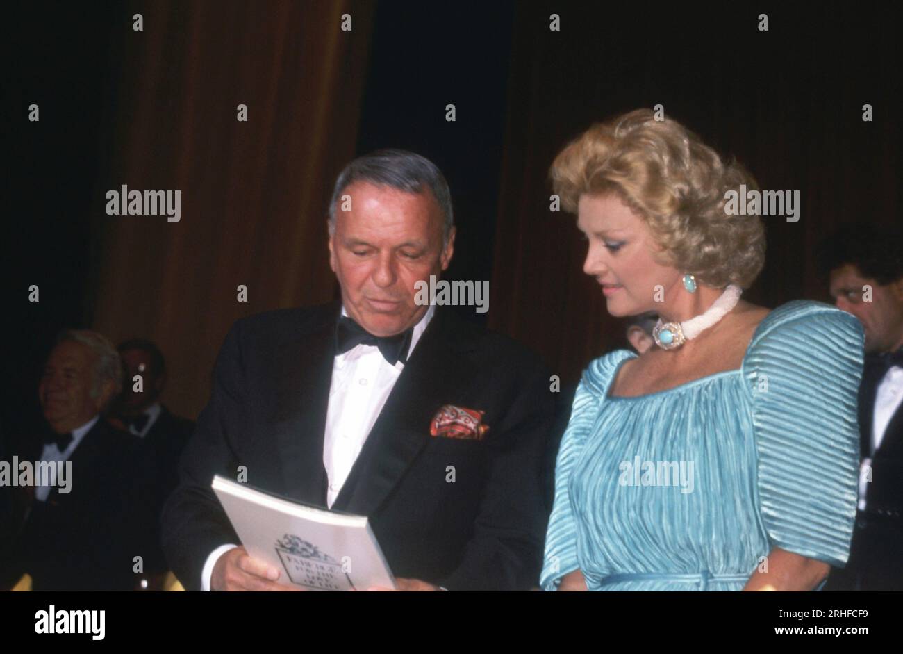 Frank Sinatra wearing black tie, with his wife Barbara wearing a blue ...