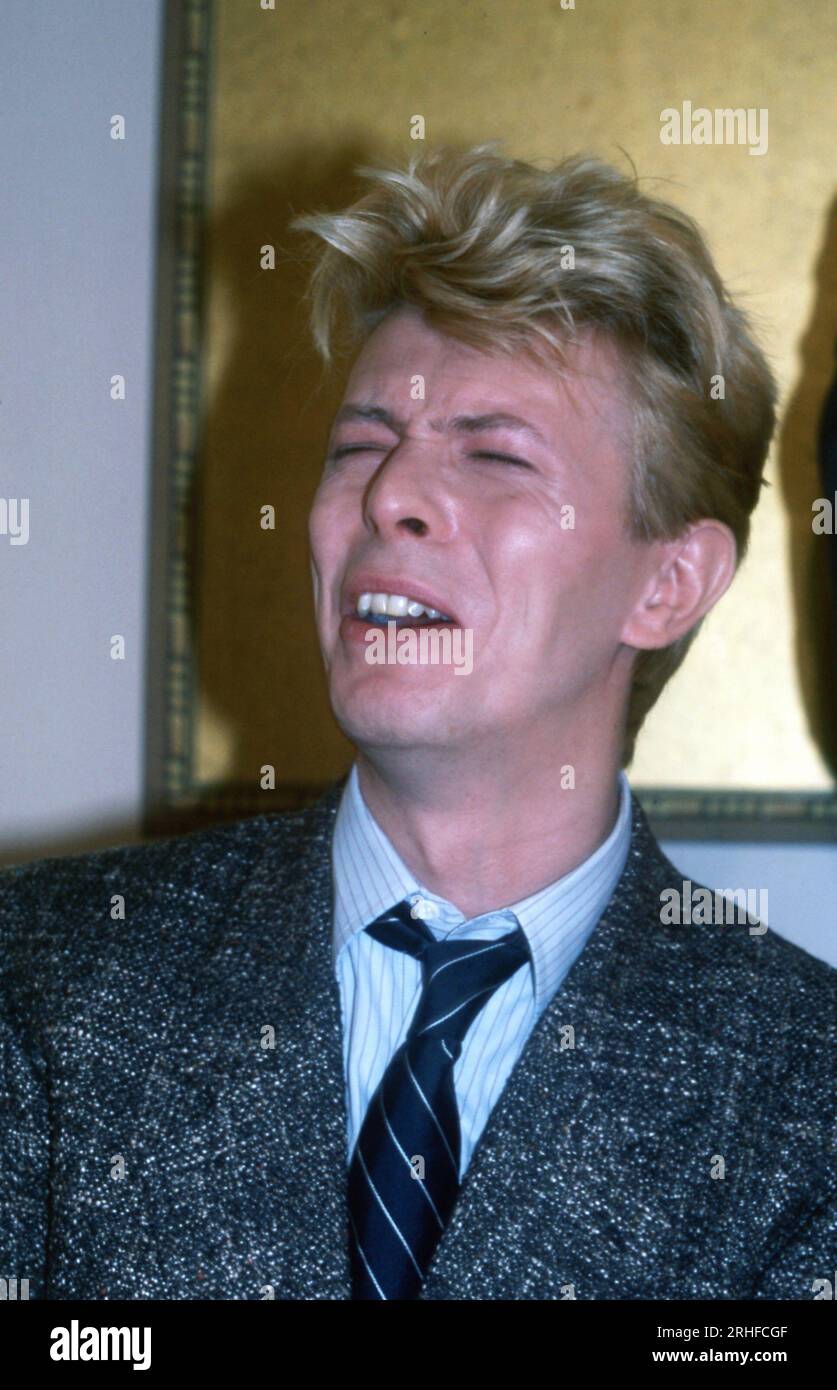 David Bowie in close-up, smiling, wearing a grey tweed jacket with tie ...