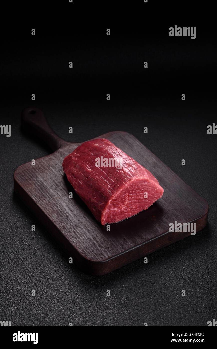 Juicy fresh raw beef meat with salt, spices and herbs on a dark ...