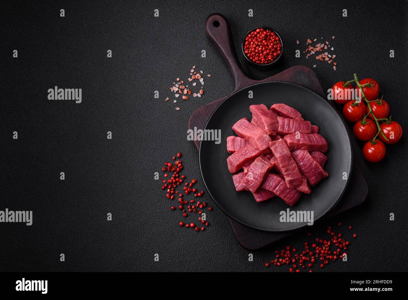 Juicy fresh raw beef meat with salt, spices and herbs on a dark ...