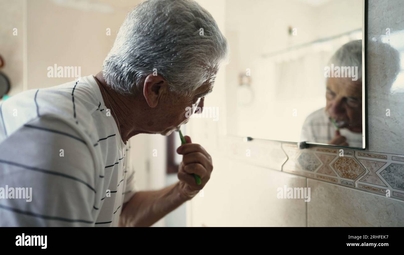 Senior morning routine brushing in mirror while staring at his own ...