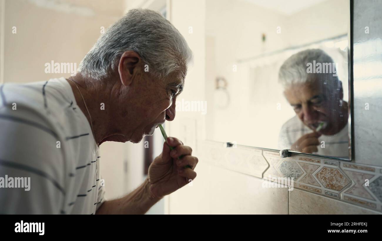 Senior morning routine brushing in mirror while staring at his own ...