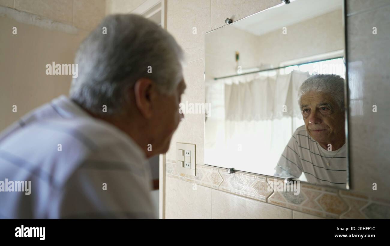 Older male caucasian man staring at his own reflection in bathroom ...
