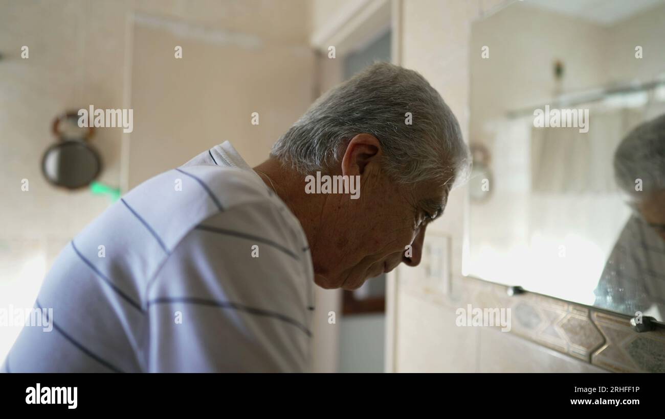 Older male caucasian man staring at his own reflection in bathroom ...