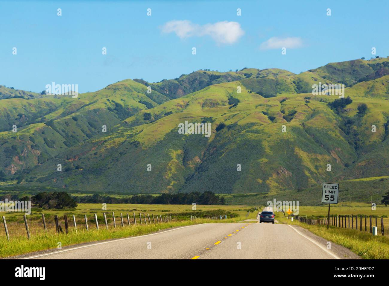 Road stretches into the distance against the backdrop of green meadows ...