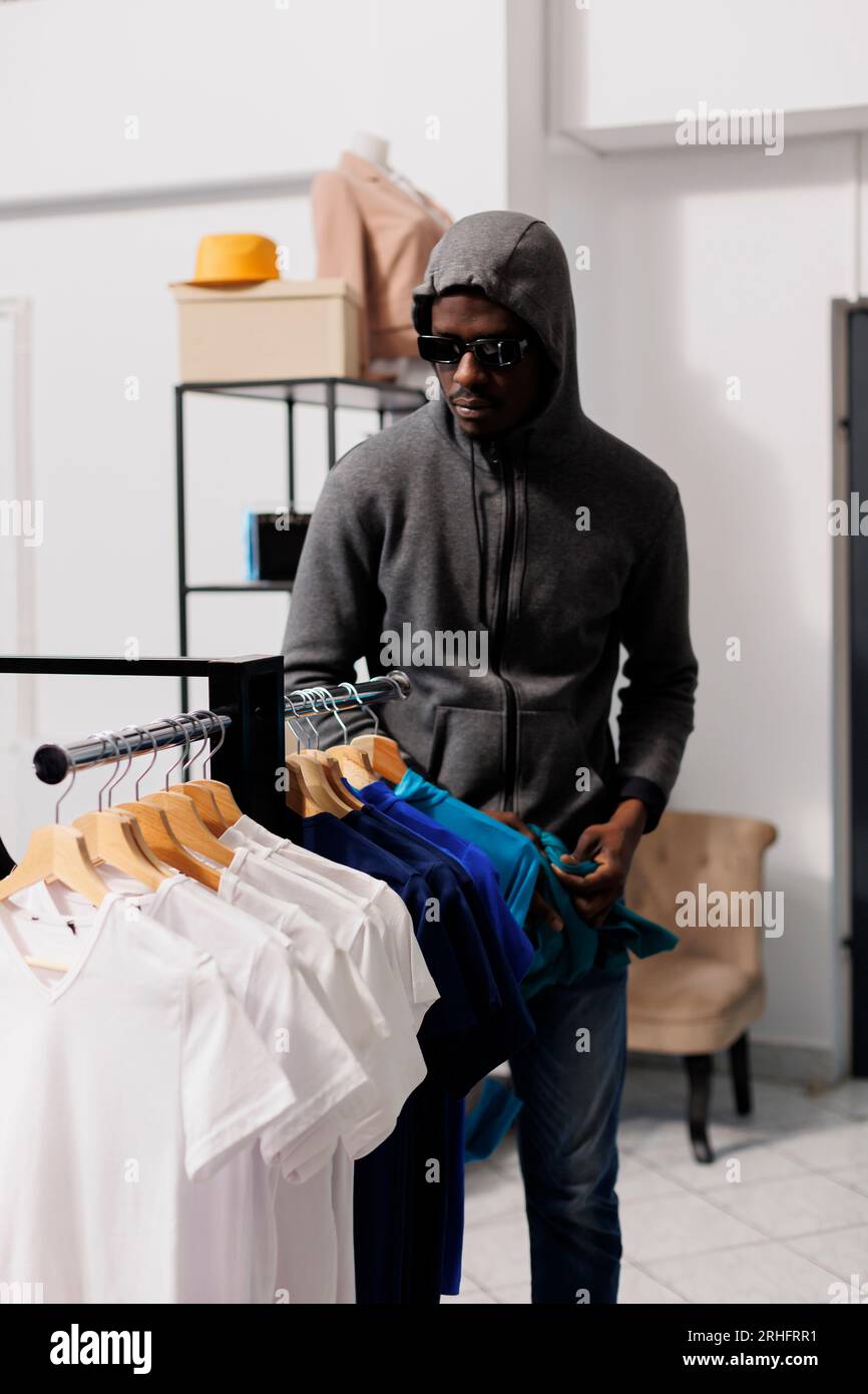 African american thief wanting to steal trendy clothes, trying not to ...